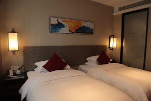Quarto de hotel com duas camas, um mapa na parede e abajures.