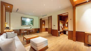 Quarto de hotel moderno com piso de madeira, sofá, mesa de jantar e closet espaçoso.