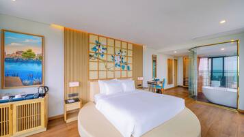 Quarto de hotel moderno com uma cama grande, uma mesa consola de madeira, uma escrivaninha, uma cadeira, um janelão e uma banheira.