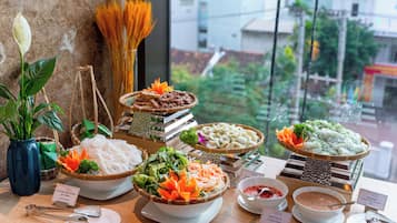 Uma mesa de buffet com diversos pratos, incluindo macarrão, legumes e arroz.