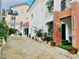 Um pátio com calçada, rodeado por edifícios com varandas e plantas em vasos.