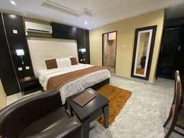 Quarto de hotel moderno com uma cama grande, uma escrivaninha, uma cadeira e um espelho.