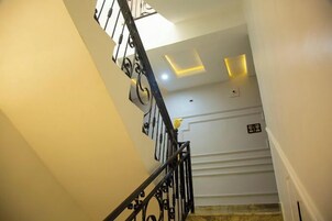 Uma escadaria com guarda-corpo de metal preto e um ponto de luz na parede.