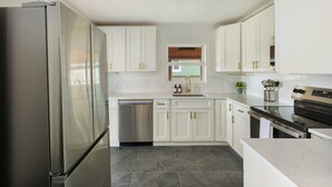 Uma cozinha moderna com armários brancos, eletrodomésticos de aço inoxidável e piso revestido de azulejos.