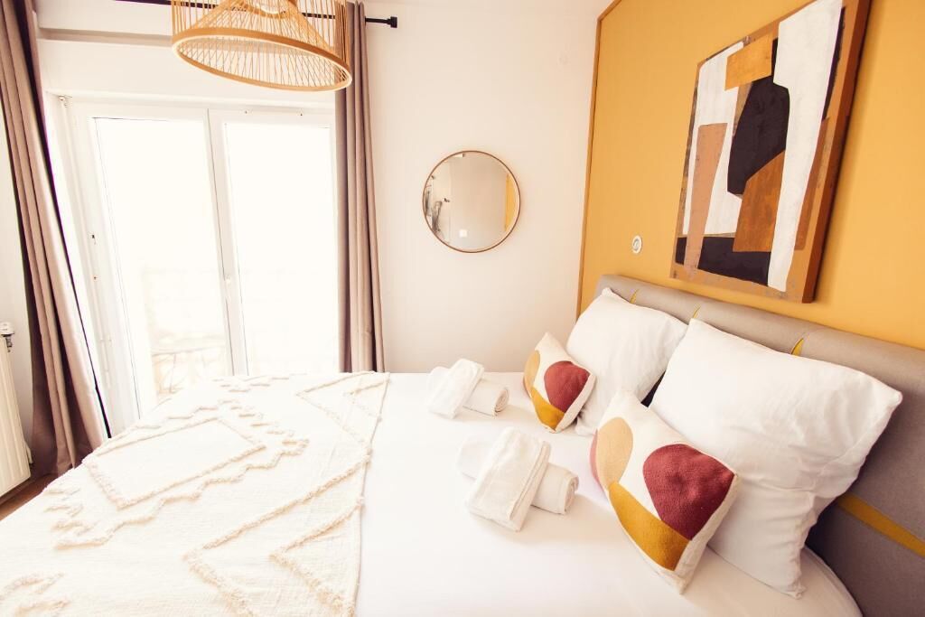Quarto de hotel com uma cama, um espelho redondo e um quadro na parede.