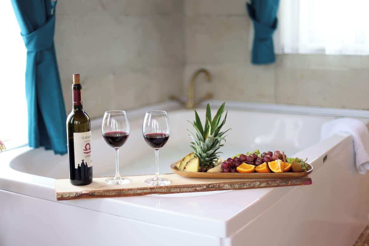 Uma banheira com uma bandeja de frutas e copos de vinho.