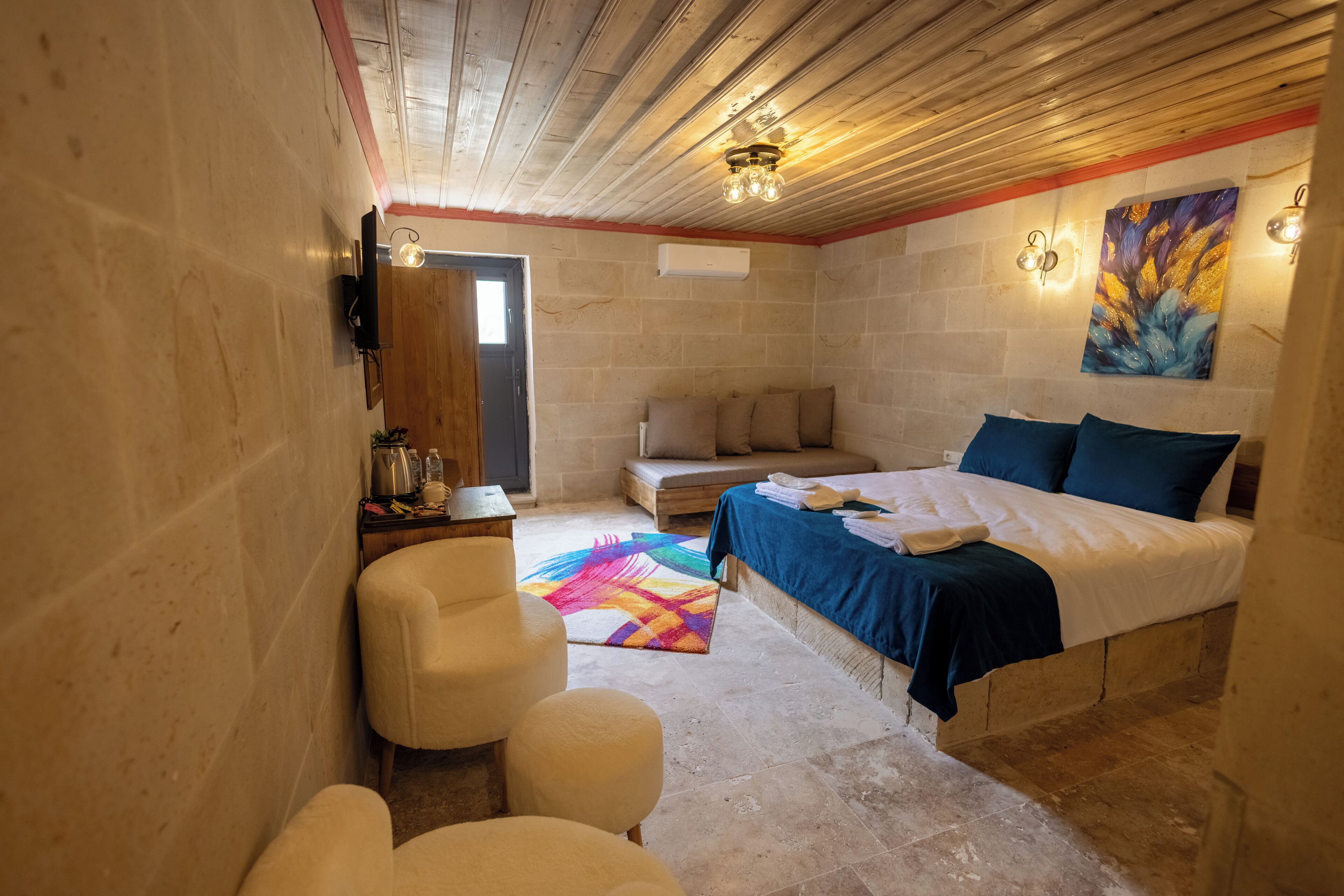 Quarto com cama, poltrona, sofá, tapete colorido e pintura na parede.