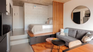 Um espaço de estar moderno e compacto, com cama, sofá e uma pequena área de refeições.