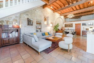 Uma sala de estar ampla com sofá, cadeiras, mesa de centro e estante.