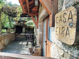 Um edifício rústico de pedra com uma placa de madeira que diz 'CASA EIRA'.