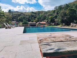 Uma piscina com espreguiçadeiras e um deque de madeira.