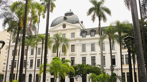 Um edifício grande com cúpula, cercado por palmeiras e um gramado bem cuidado.