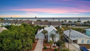 Zona residencial à beira-mar, com casas, praia e um pôr do sol.