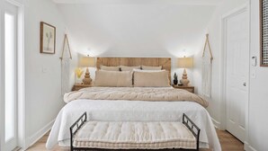 Quarto com cama, ventoinha no teto, abajures e uma porta.