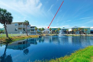 Uma propriedade à beira-mar com lago, cerca branca e vários edifícios com varandas.