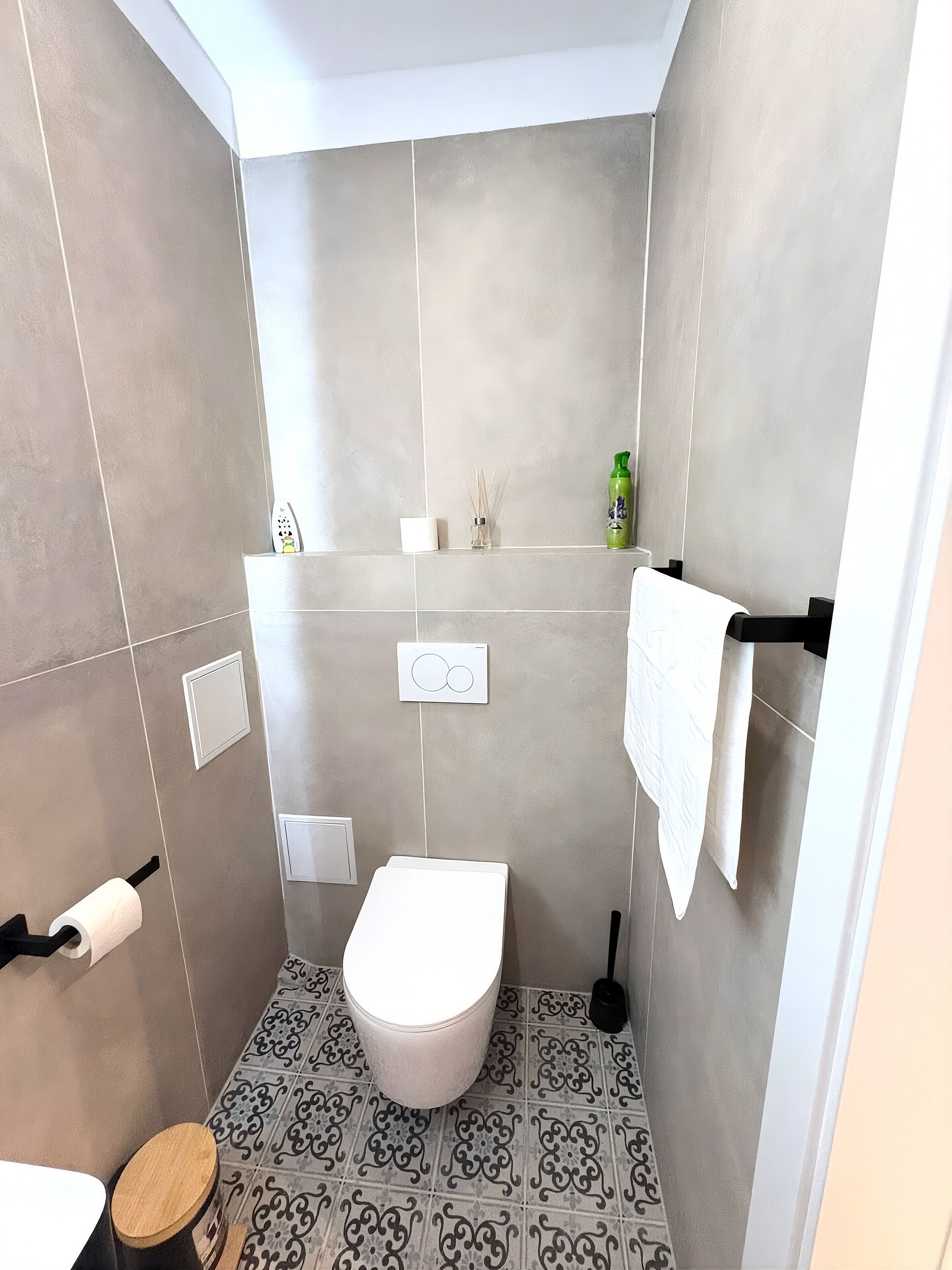 Uma casa de banho com sanita, lavatório, espelho e zona de duche.