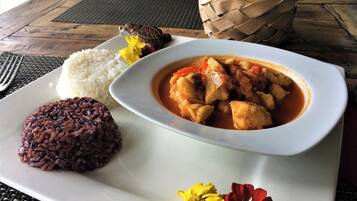 Uma refeição com arroz, arroz preto e um ensopado de legumes e carne, servida em um prato branco.