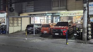 Uma área de estacionamento com vários carros, um salão e uma loja chamada 'Lorenzo Suit'.