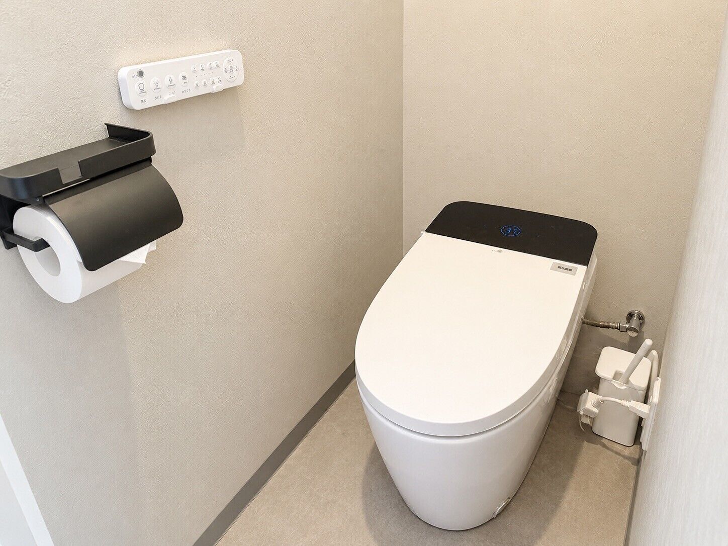 Casa de banho moderna com painel de controlo, suporte para papel higiénico e função bidé.