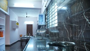 Uma cozinha com painel de parede de mármore, um bebedouro e um balcão comprido com uma panela em cima.