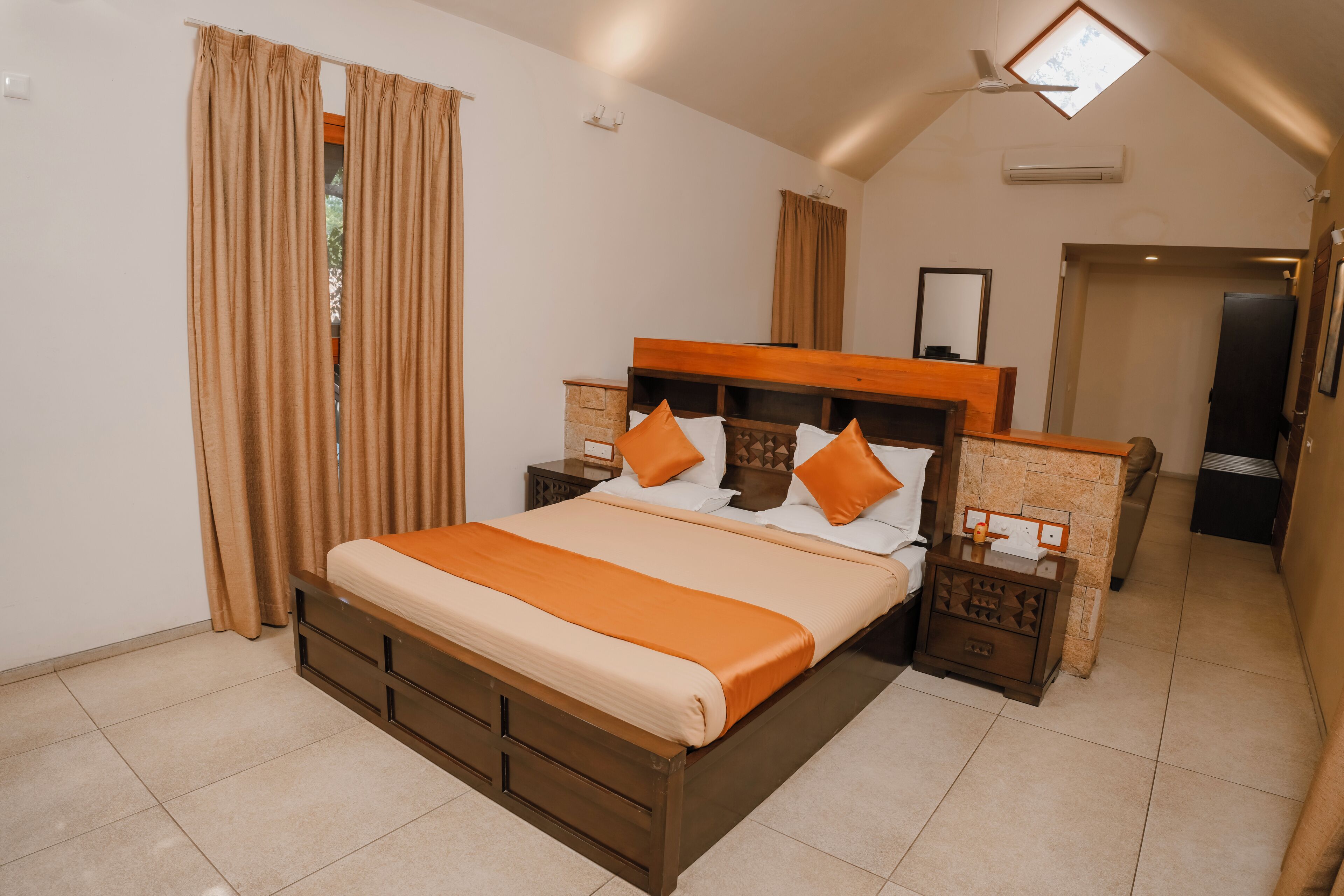 Quarto com cama grande, cabeceira de madeira, duas mesas de cabeceira, cômoda e ventilador de teto.