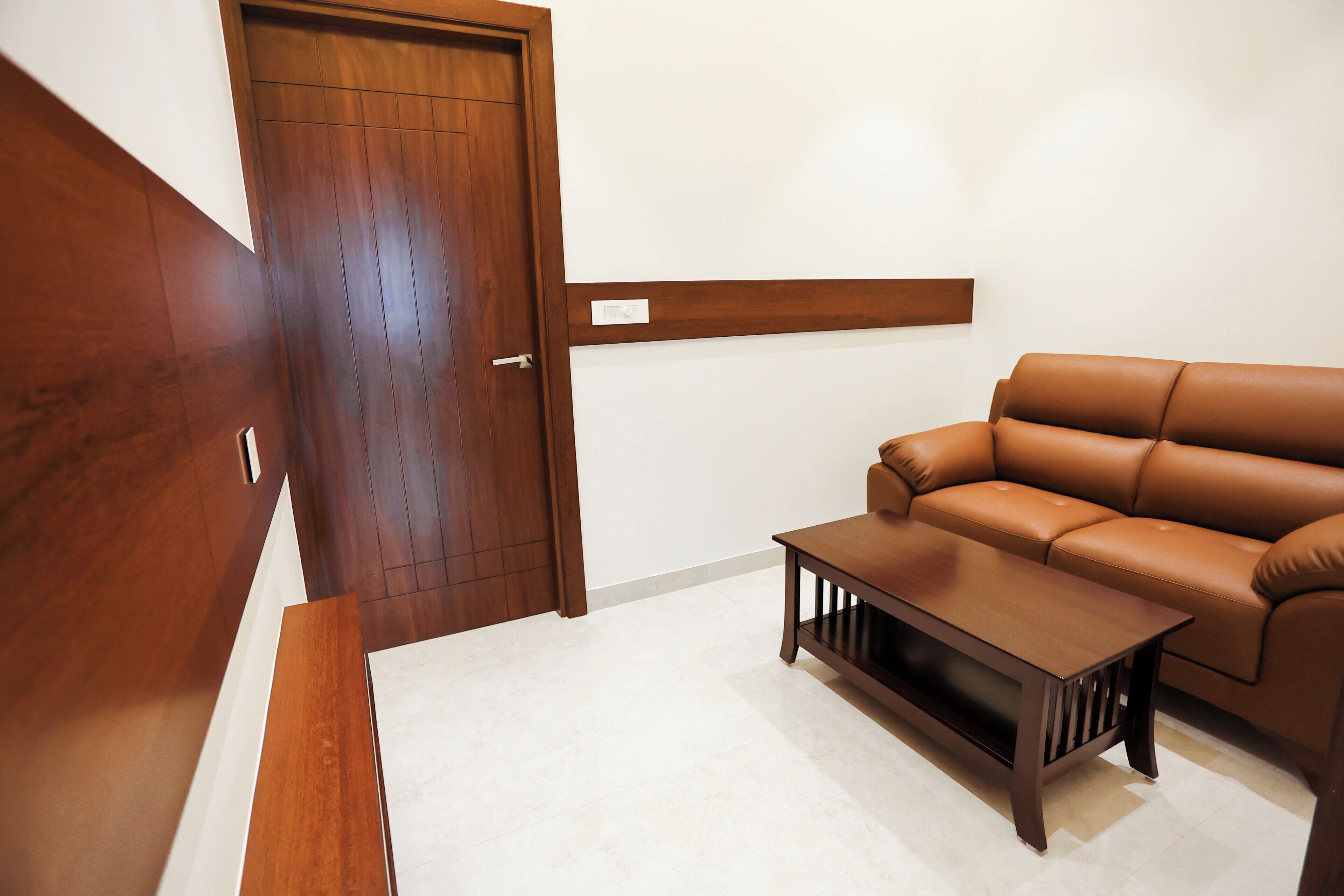Quarto com guarda-roupa de madeira, sofá de couro marrom e mesa de centro de madeira.