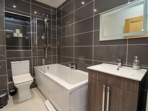 Uma casa de banho moderna com banheira, sanita e lavatório.