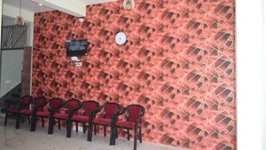 Um quarto com papel de parede estampado, um relógio e algumas cadeiras.