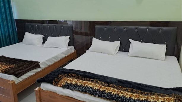 Quarto de hotel com duas camas, cada uma com cabeceira escura e roupa de cama branca.