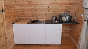 Uma cozinha compacta com paredes de madeira, pia, fogão e cafeteira.