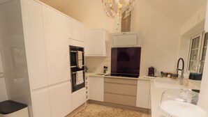 Uma cozinha compacta com armários brancos, forno embutido, fogão e pia.