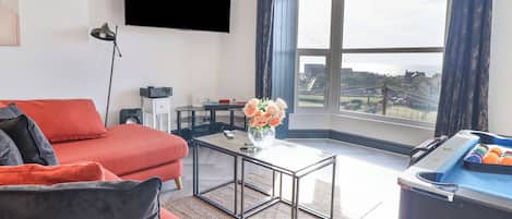 Uma sala de estar moderna com um sofá vermelho, uma mesa de centro e uma janela grande com vista para o exterior.