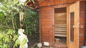Uma cabana de madeira com a porta aberta, mostrando um banco de madeira no interior.