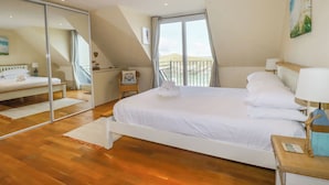 Quarto com uma cama grande, uma cadeira, uma escrivaninha e vista para o exterior.