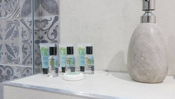 Uma bancada de banheiro com três frascos de Shampoo Revitalizante, uma embalagem de shampoo com bomba e um saboneteira.