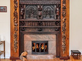 Lareira com esculturas detalhadas e moldura de pedra.