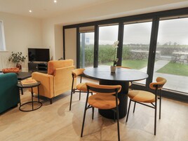 Uma sala de estar moderna com sofá, poltronas, mesa de centro e televisão.