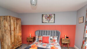 Quarto com uma cama grande, duas mesas de cabeceira, um guarda-roupa de madeira e uma obra de arte na parede.