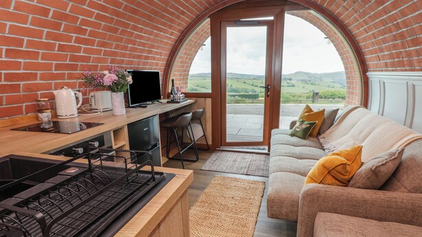 Um interior acolhedor com cozinha, sofá e uma grande janela com vista para o campo.