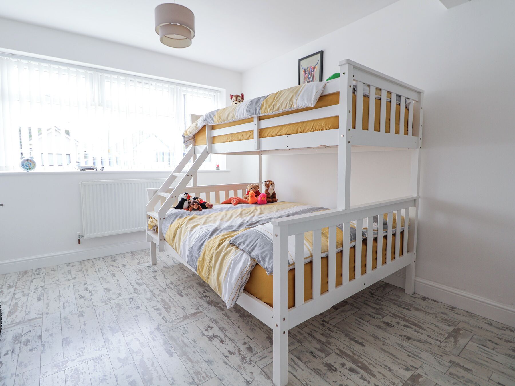 Quarto com beliche, janela, radiador e brinquedos na cama.