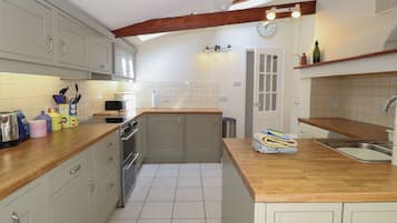 Uma cozinha com bancada de madeira, eletrodomésticos de aço inoxidável e armários em tons claros.
