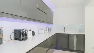 Um frigorífico, uma máquina de lavar louça, utensílios de cozinha