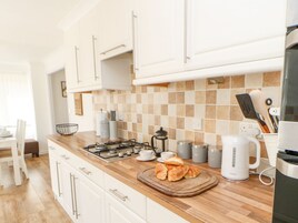 Cozinha moderna com armários brancos, bancada de madeira e painel de azulejos.