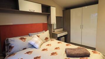 Quarto de hotel com cama, escrivaninha, guarda-roupa e espelho.