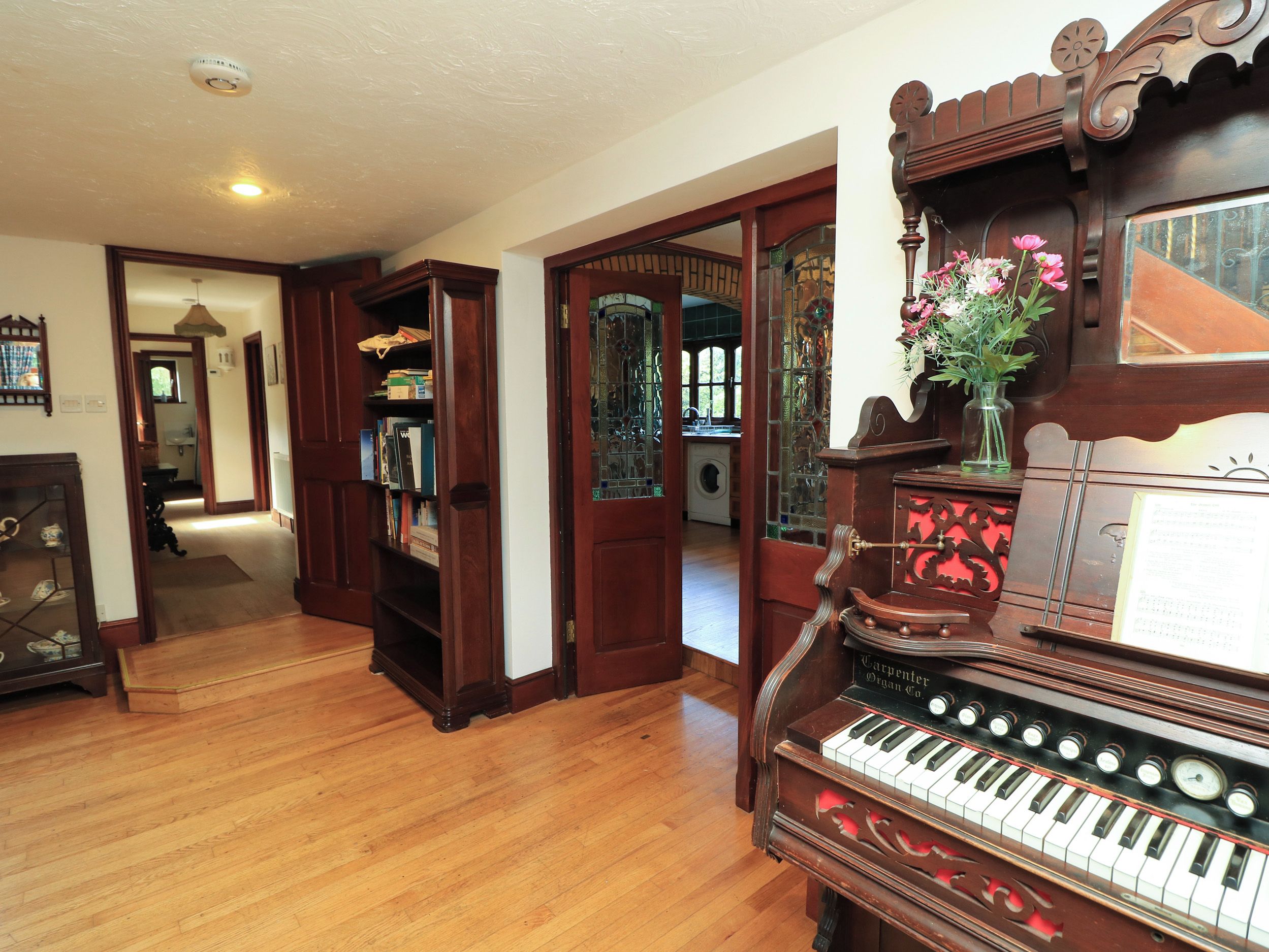 Piso de madeira, um piano e uma porta com painéis de vidro.