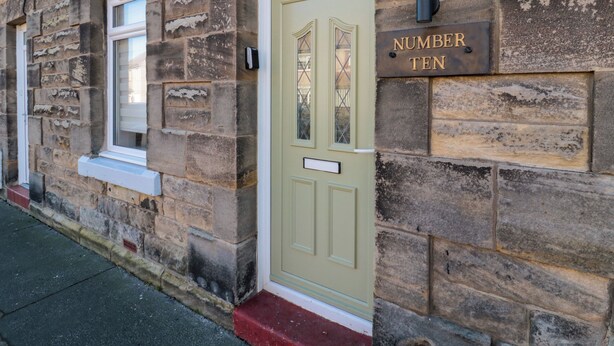 Um edifício de pedra com uma porta verde e uma placa com a inscrição 'NUMBER TEN'.