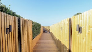 Um deck de madeira leva a uma área de piscina, com cercas de madeira em ambos os lados.