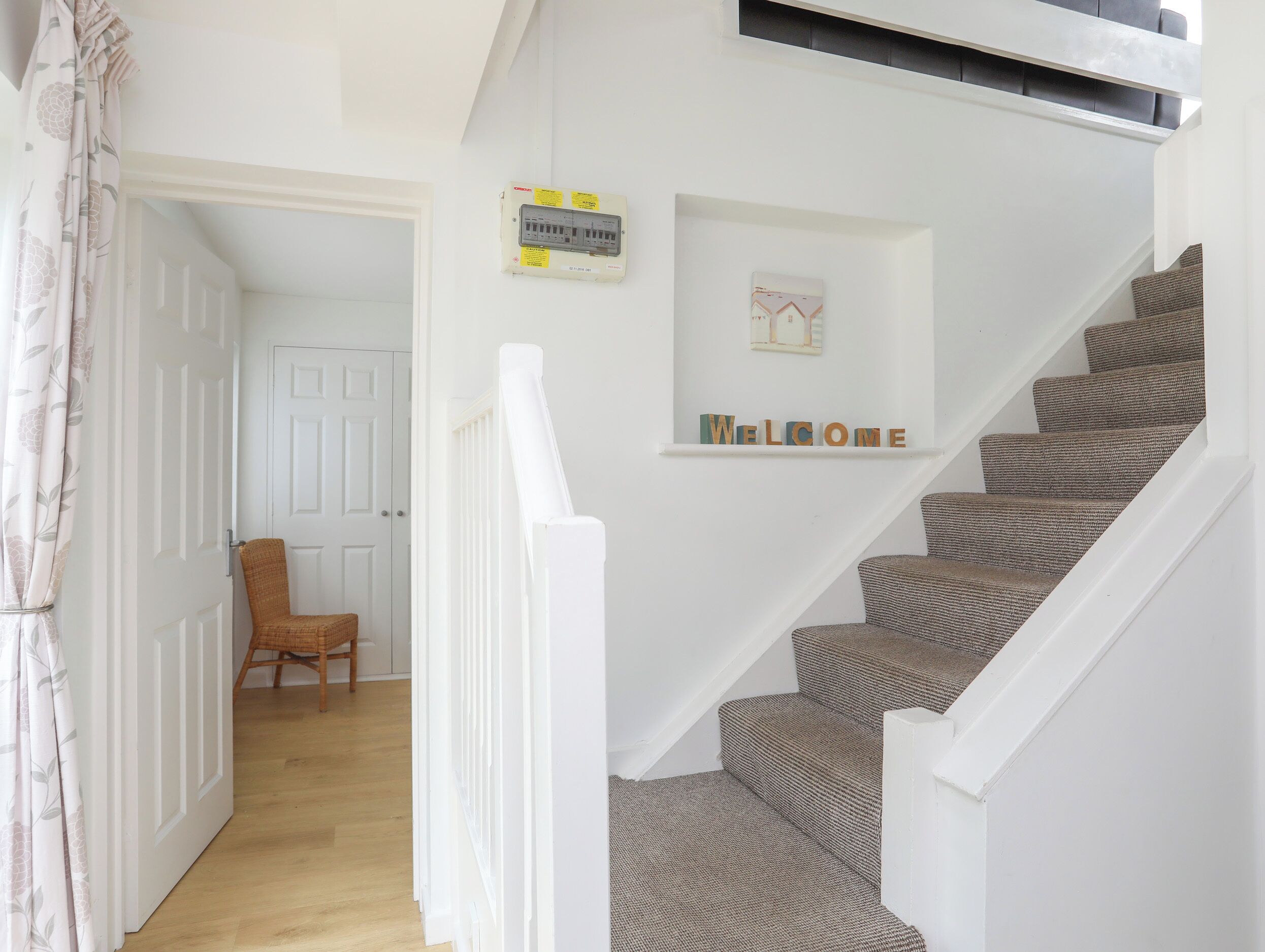 Uma escada com uma placa de 'WELCOME', uma tomada e um quadro na parede.