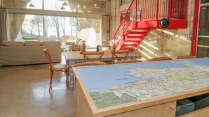 Um quarto espaçoso com um mapa grande sobre uma mesa, uma escadaria vermelha e um sofá.
