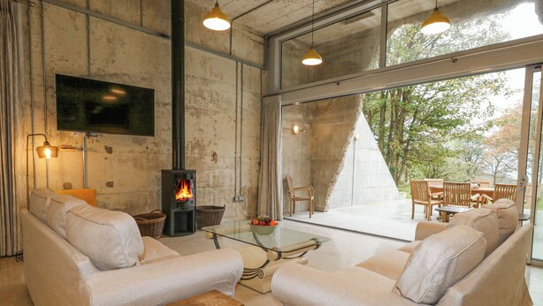 Uma sala de estar moderna com lareira, assentos confortáveis e uma grande janela com vista para o exterior.